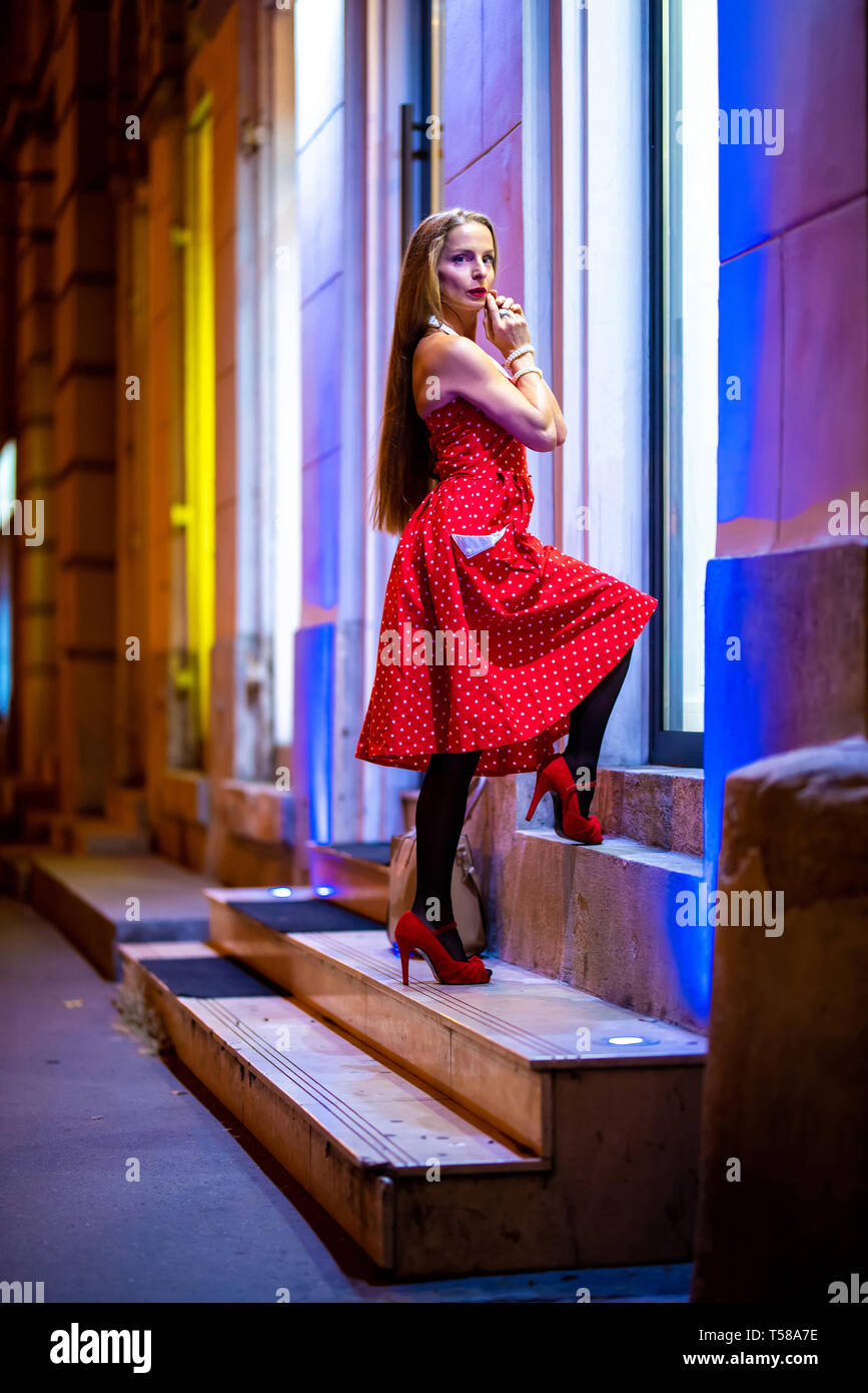 A beautiful mature woman in a red dress checking the storefront at ...
