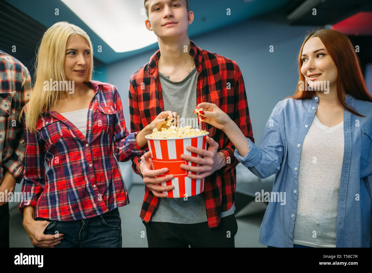 Group of friends with popcorn in cinema hall Stock Photo - Alamy