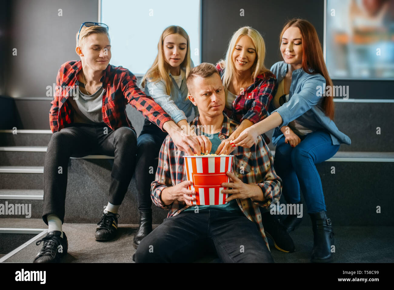 Group of friends poses with popcorn in cinema hall Stock Photo - Alamy