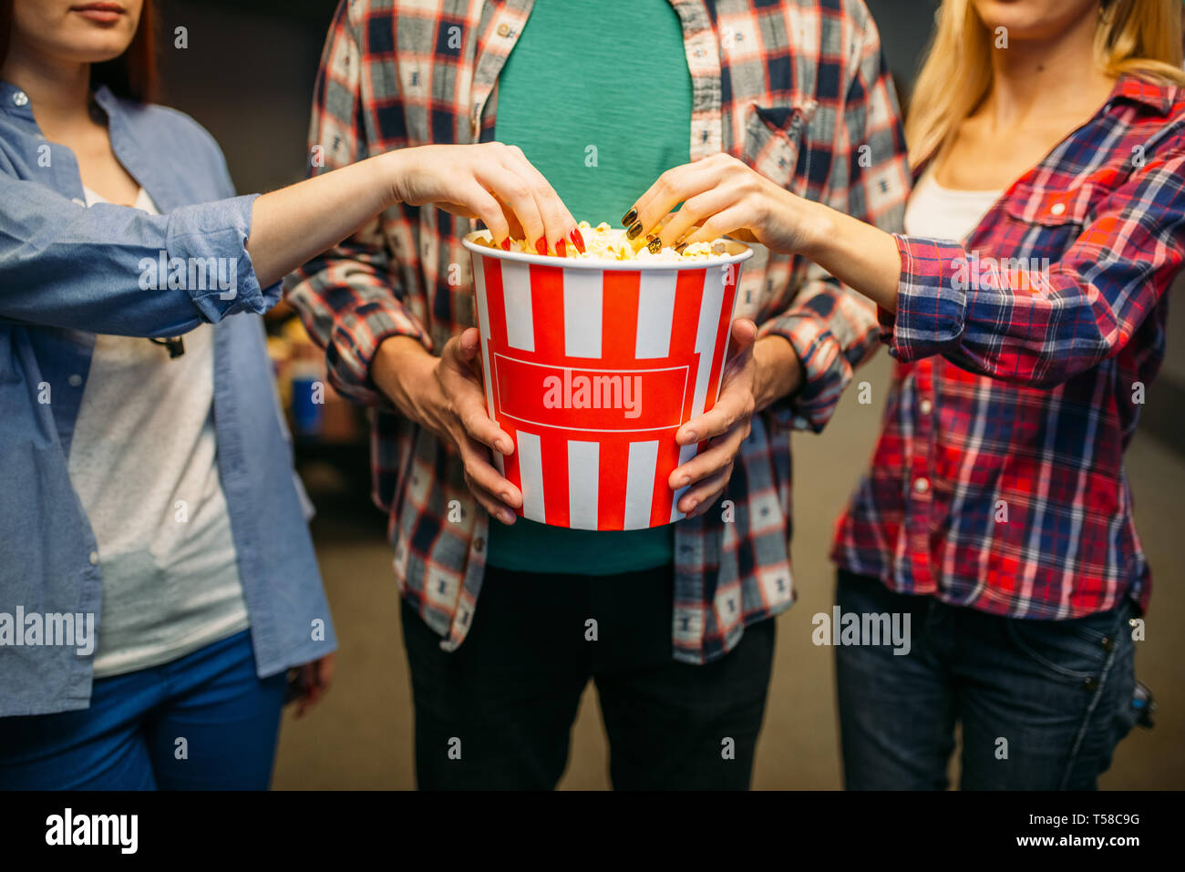 Group of friends poses with popcorn in cinema hall Stock Photo - Alamy