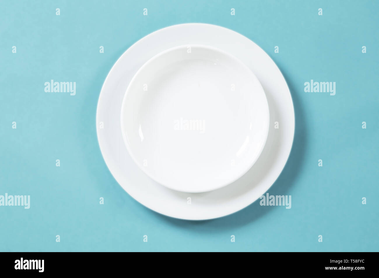 White plates on blue background - top view Stock Photo - Alamy