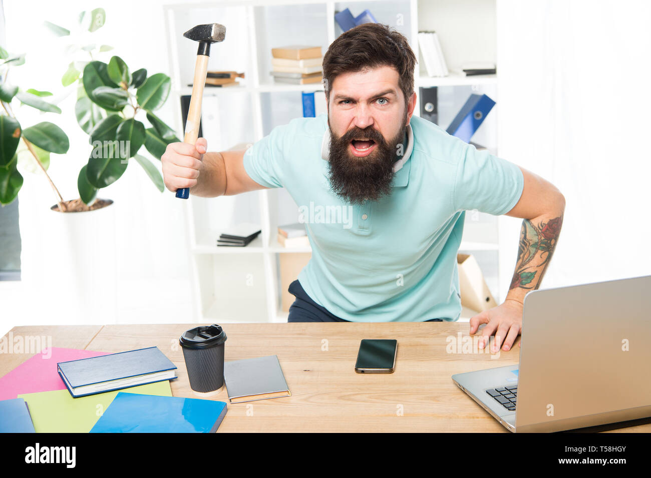 Frustrated office worker holding hammer poised ready to smash. Office ...