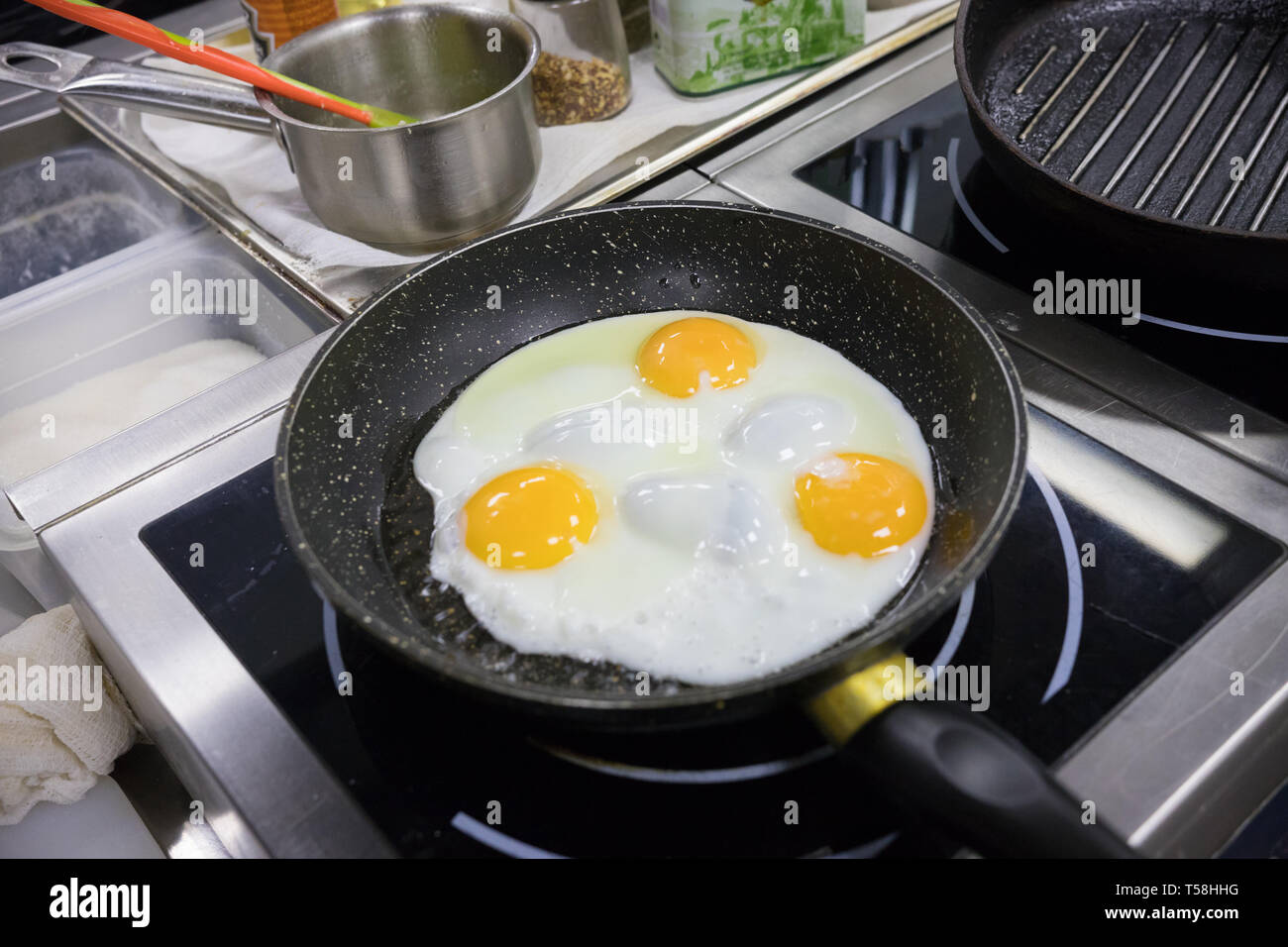 Restaurant kitchen. Chef frying eggs in the pan Stock Photo - Alamy