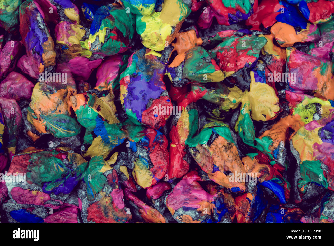 Pebbles painted bright colored paint. Stony surface covered with ...