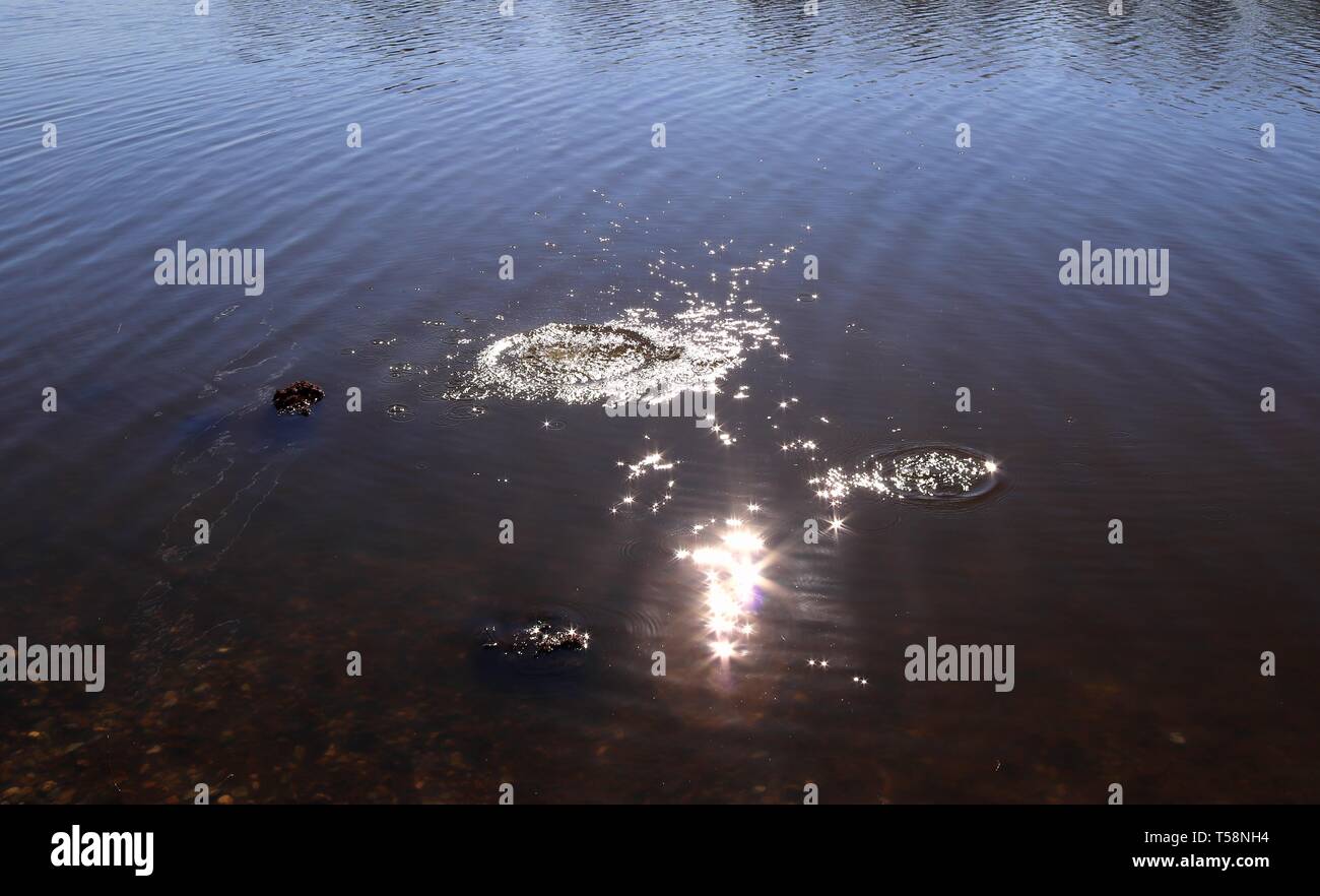 Blue lake water surface with ripples and splashing item falling into it ...