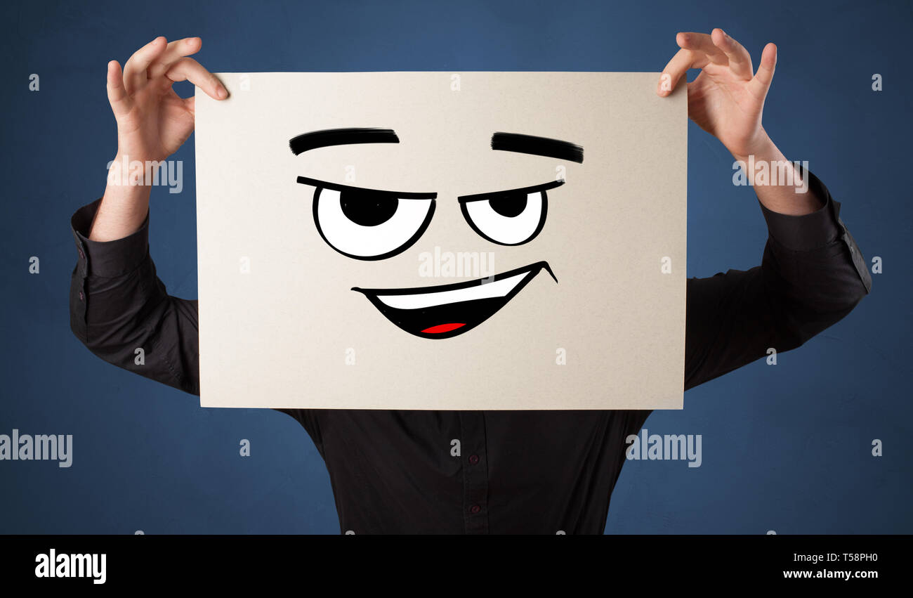 Casual person holding a paper in front of his face with drawn emoticon ...