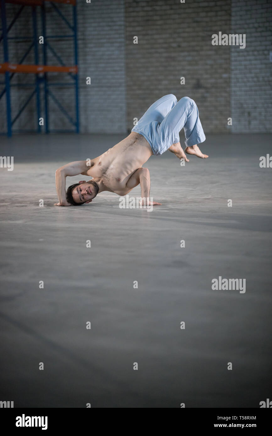 An athletic man on capoeira training. Standing on one hands in an ...