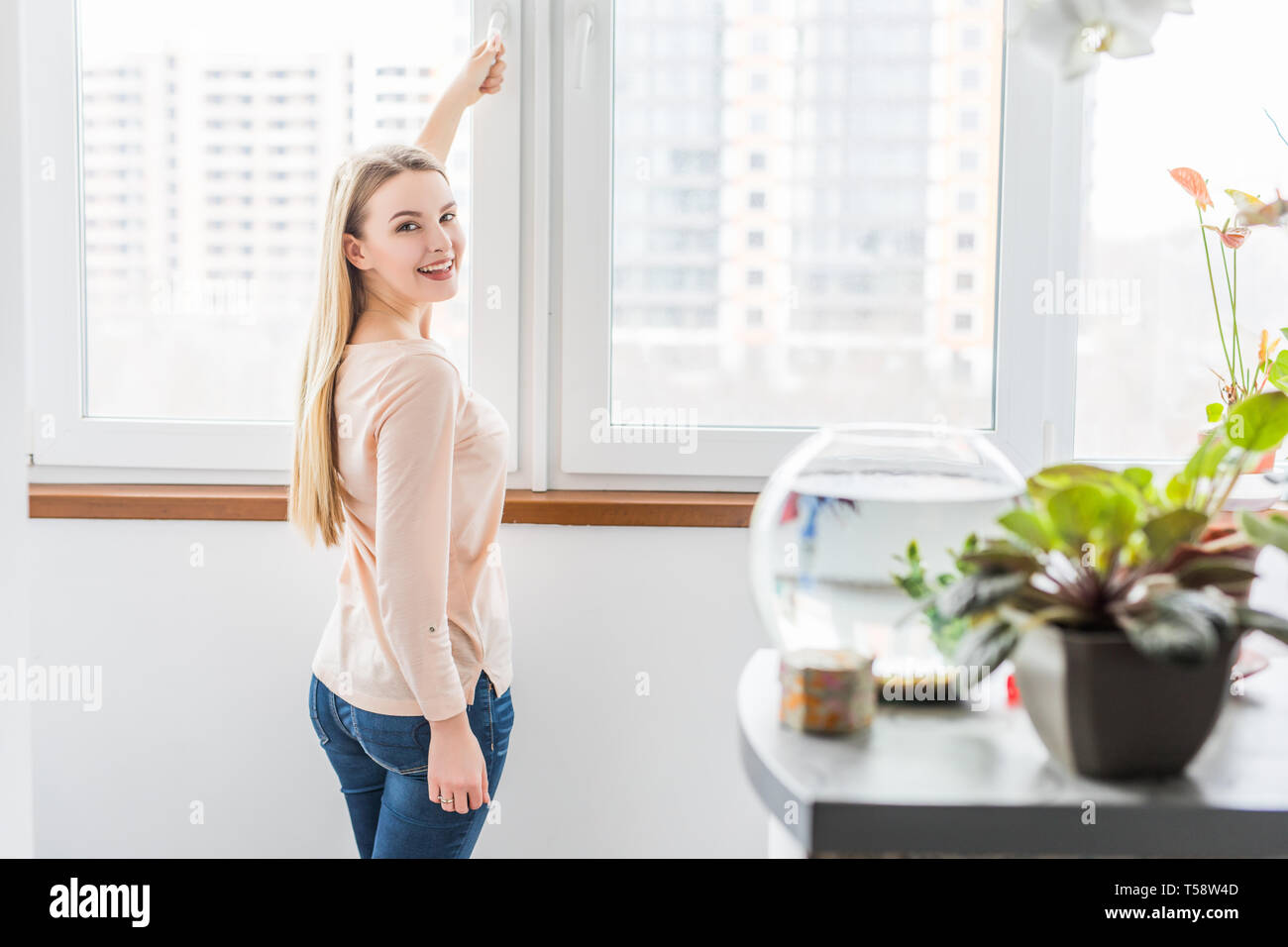 Back view of woman looking outdoors through a window and opening window ...