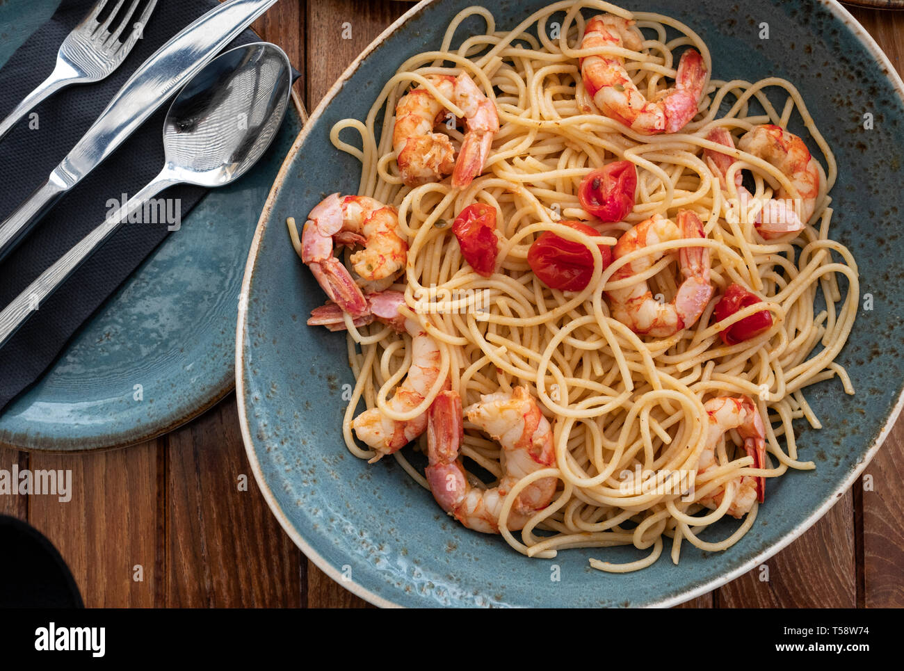 blue dish of spaghetti with prawns and pieces of tomatoes Stock Photo ...