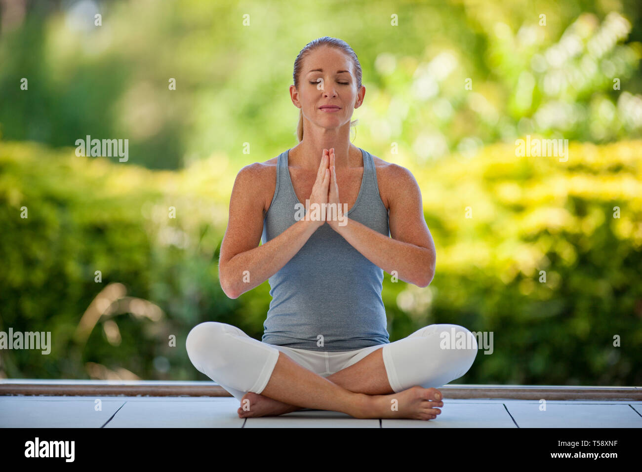 Relaxed mid adult woman meditating on a deck Stock Photo - Alamy