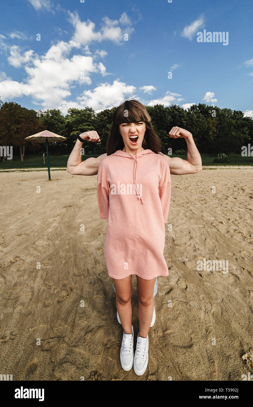 The girl shows her muscles. A woman in a summer dress shows her biceps ...