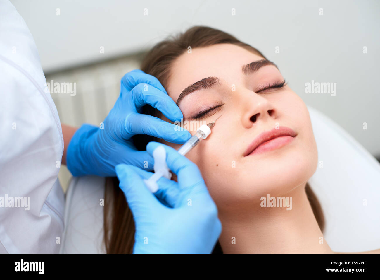 Doctor in medical gloves with syringe injects botulinum under eyes for ...