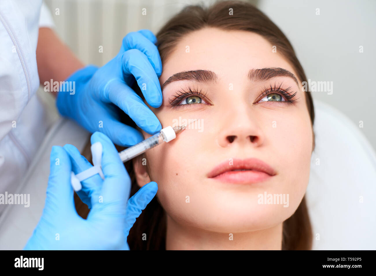 Doctor in medical gloves with syringe injects botulinum under eyes for ...