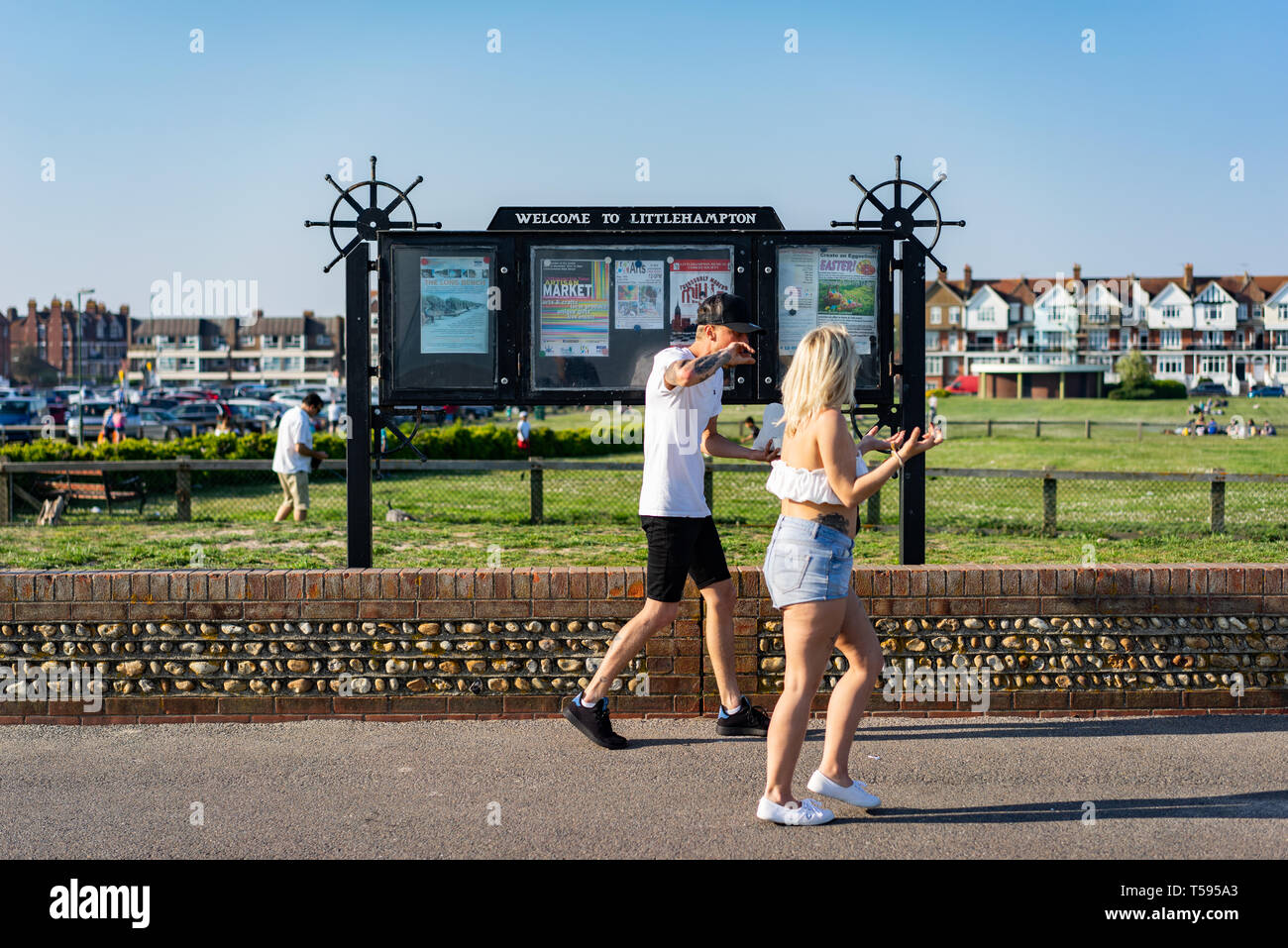 A young couple eating fast food walking along the promenade in ...