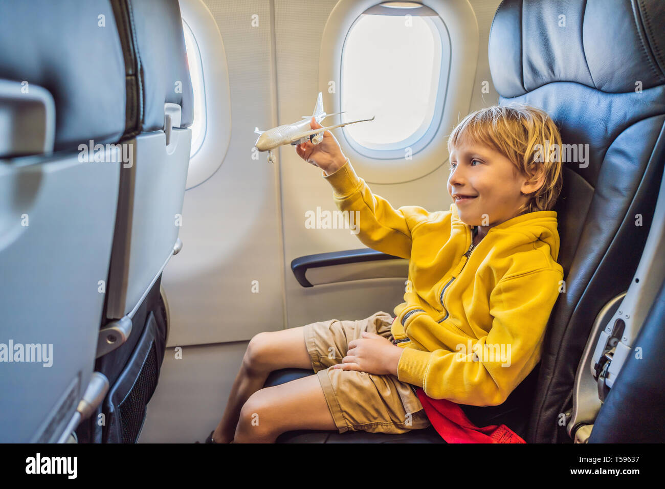 Little boy play with toy plane in the commercial jet airplane flying on ...