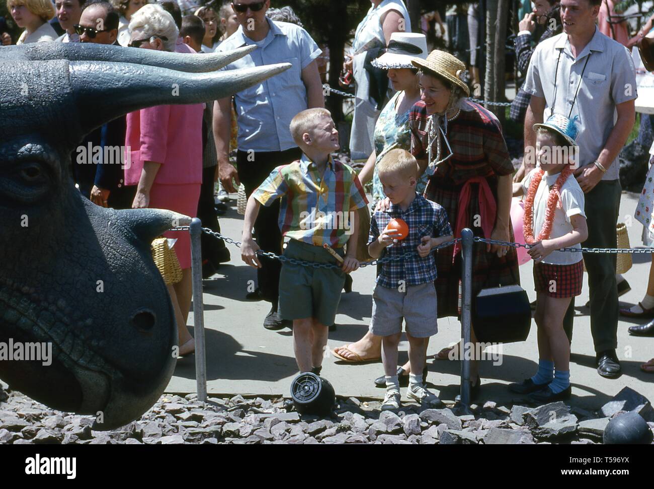 A crowd of people, on a sunny day, viewing the fiberglass head of a ...
