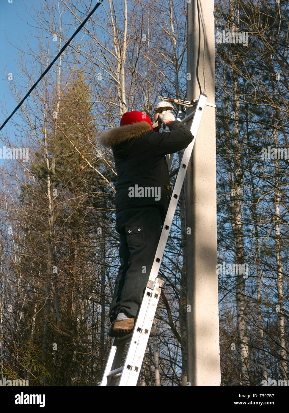 Vertical image of electrician, replacing bulb, while standing on an ...