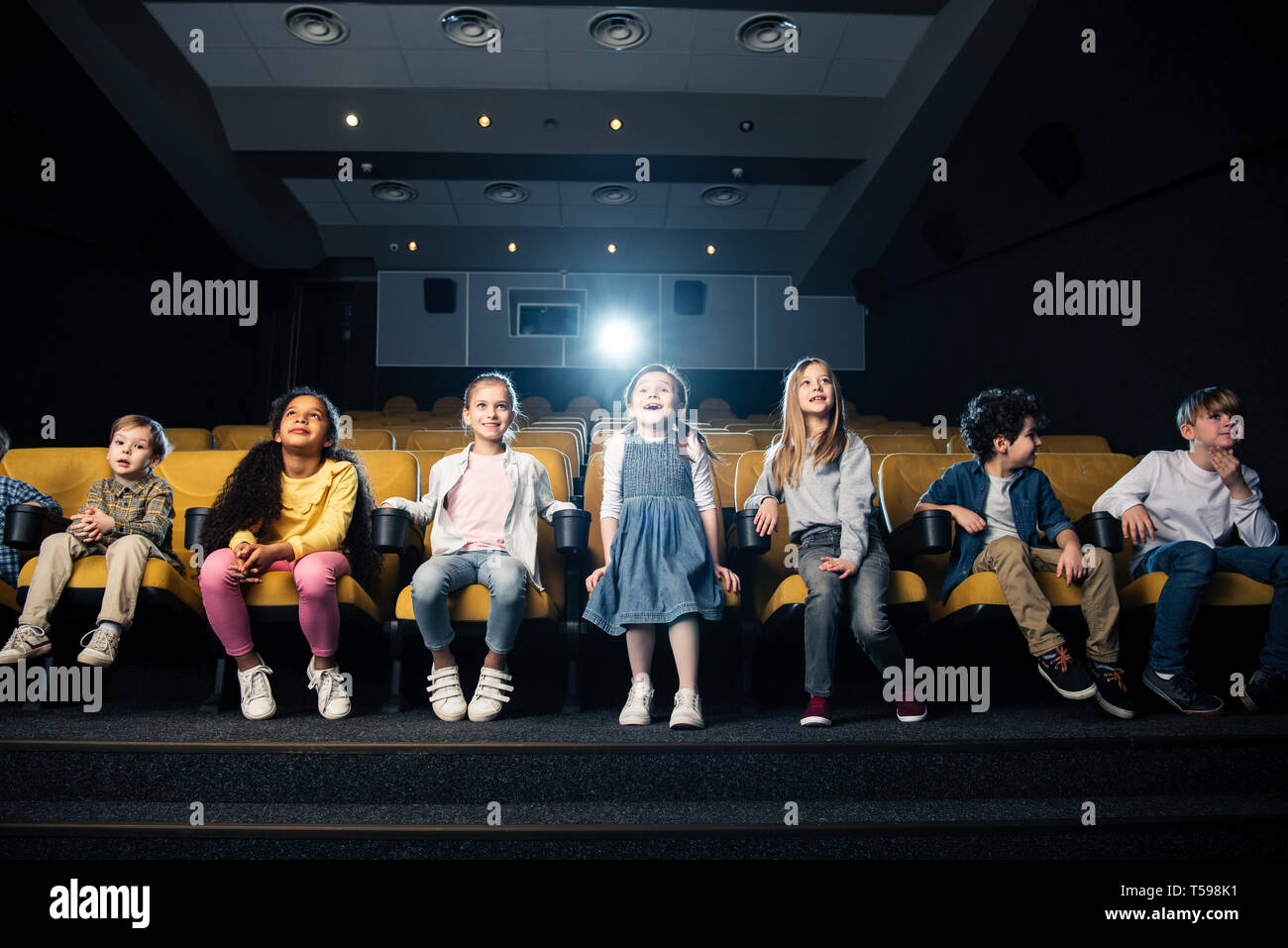 group of multicultural friends sitting in first row in cinema Stock ...