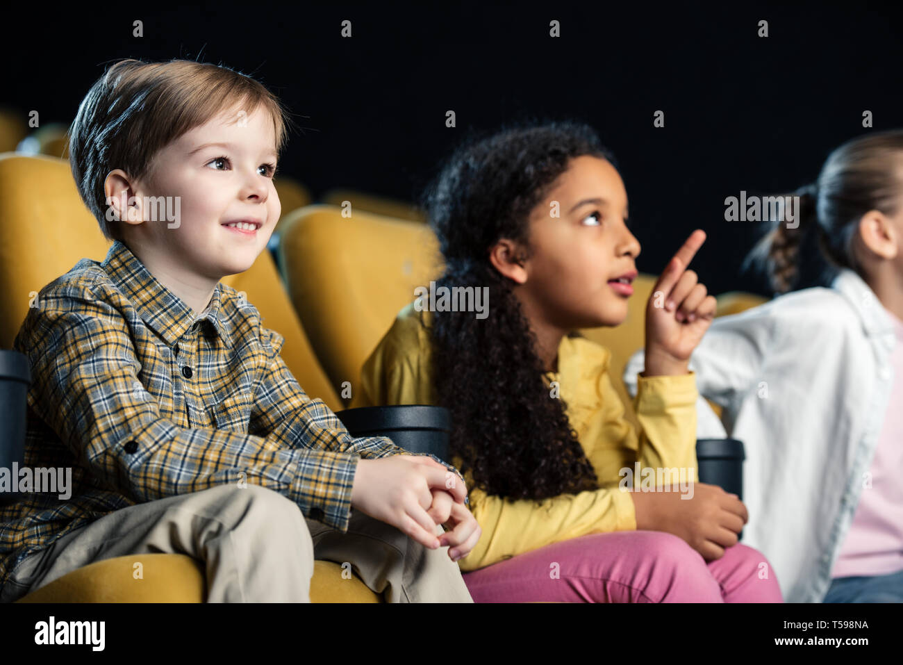 cute african american child pointing with finger while watching movie ...