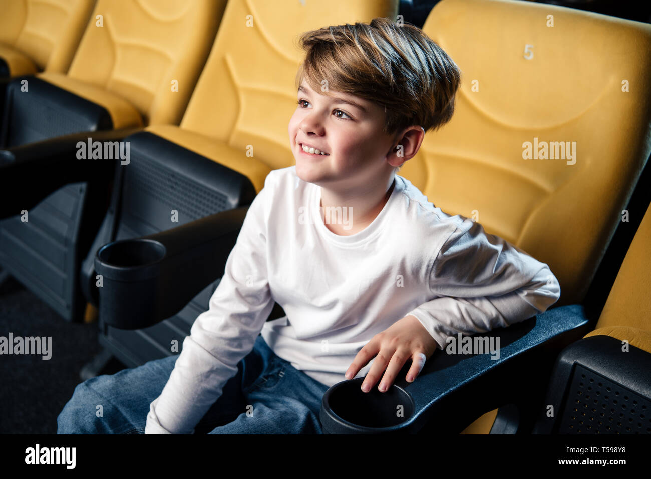 cute smiling boy sitting and cinema and watching movie Stock Photo - Alamy