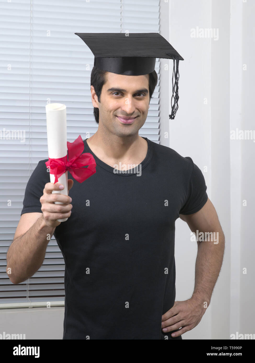 PORTRAIT OF YOUNG MAN HOLDING A DEGREE CERTIFICATE WHILE WEARING A ...