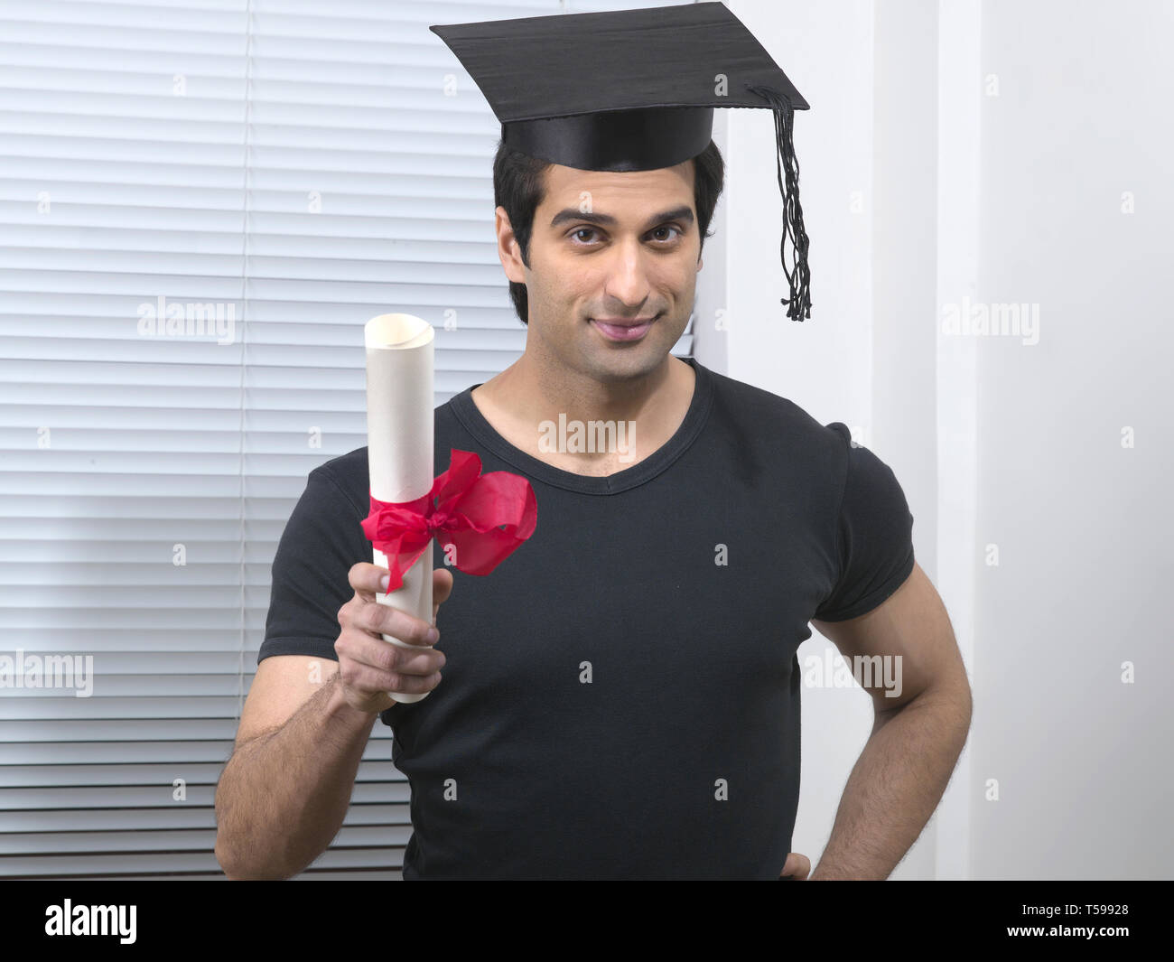 PORTRAIT OF YOUNG MAN HOLDING A DEGREE CERTIFICATE WHILE WEARING A ...