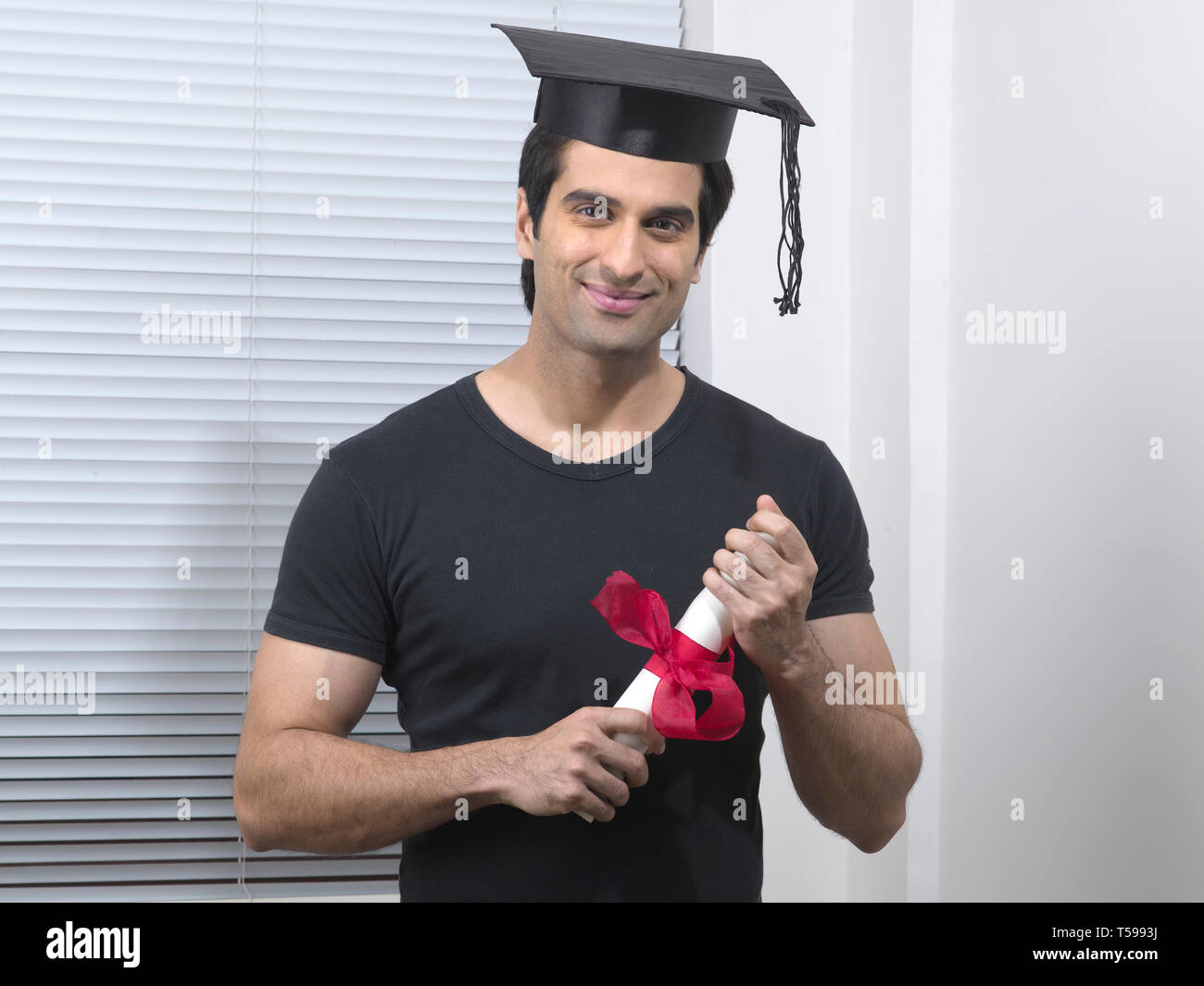 PORTRAIT OF YOUNG MAN HOLDING A DEGREE CERTIFICATE WHILE WEARING A ...