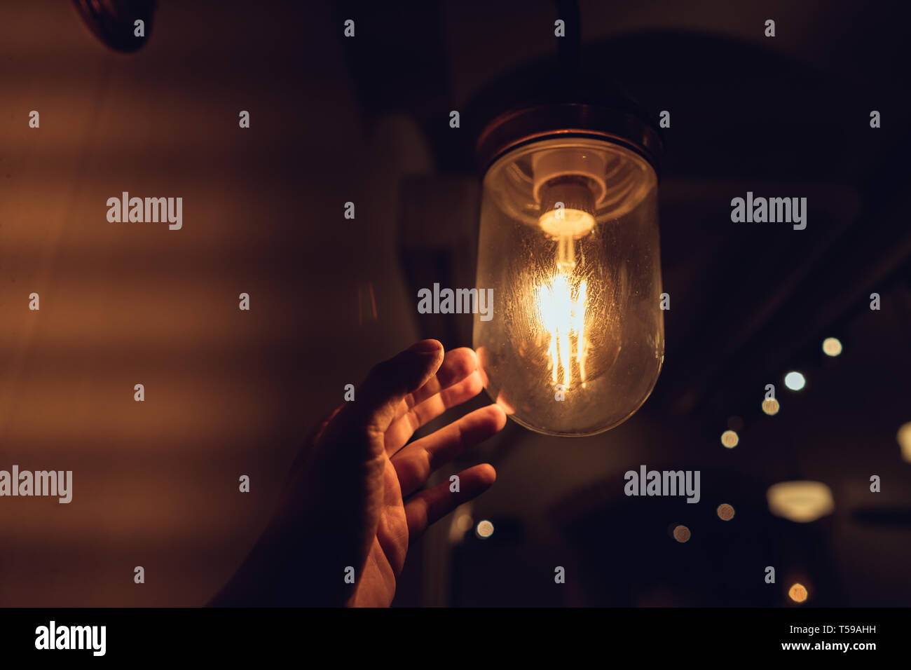 Hand reaching for a vintage light bulb Stock Photo - Alamy
