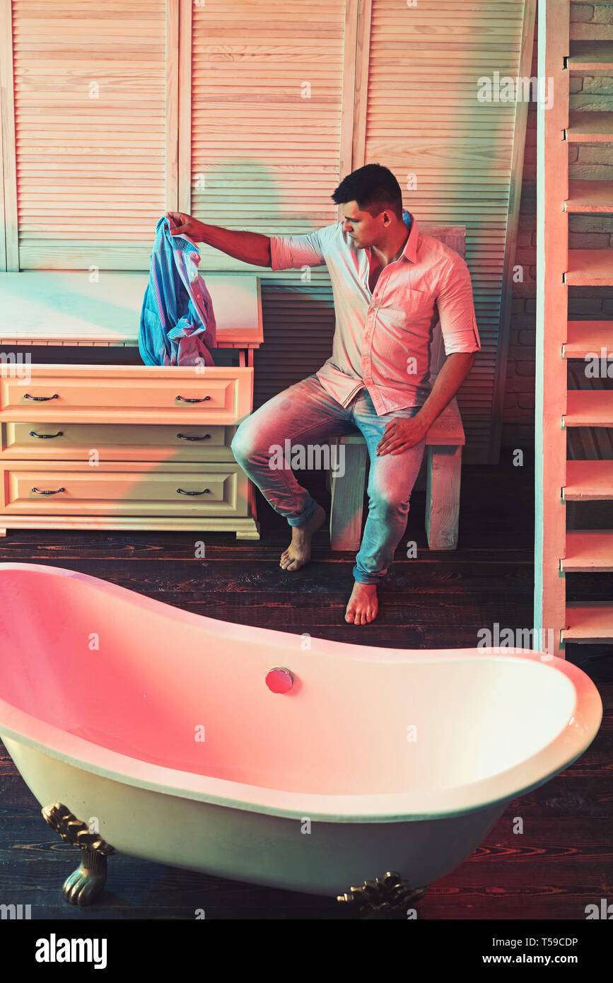 Young man putting dirty clothes into drawer Stock Photo - Alamy