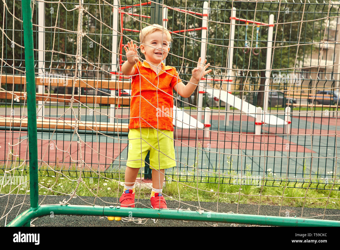 little boy on playground with a grid of football gate. playing child on ...