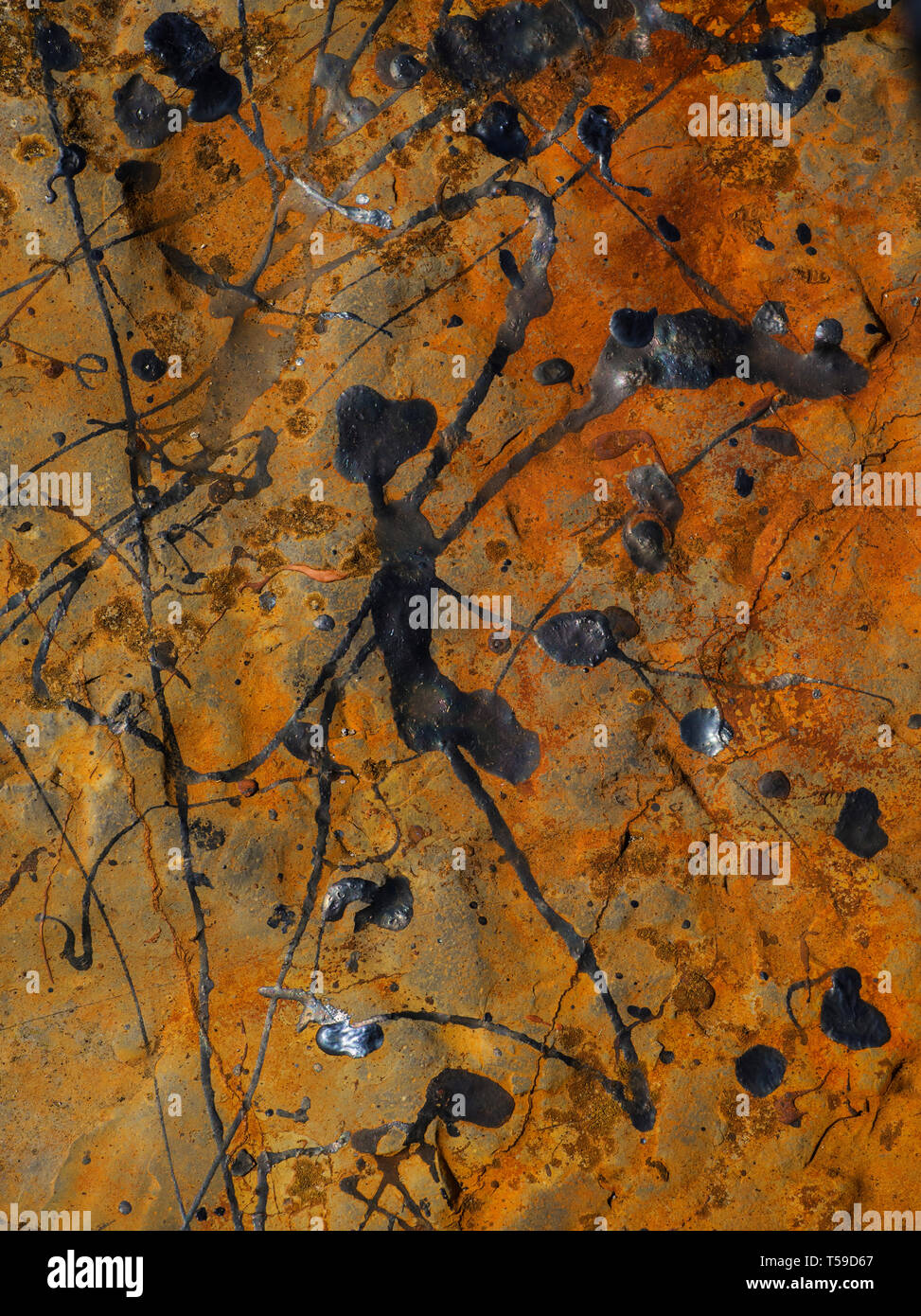 An abstract detail of rust staining and fresh black paint beneath ...
