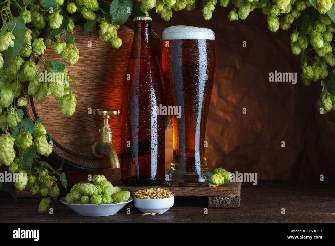Bottled and unbottled beer with barrel, barley and fresh hops for ...