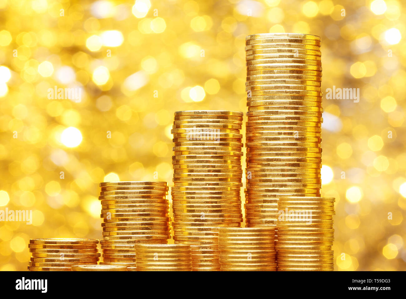 Sparkling new golden coins stacks on bright light glowing bokeh ...