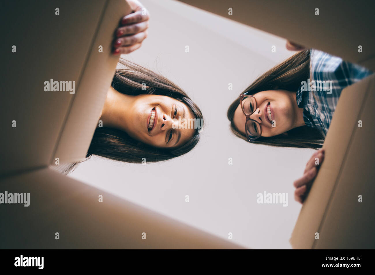 Two pretty girls opens cardboard box Stock Photo - Alamy