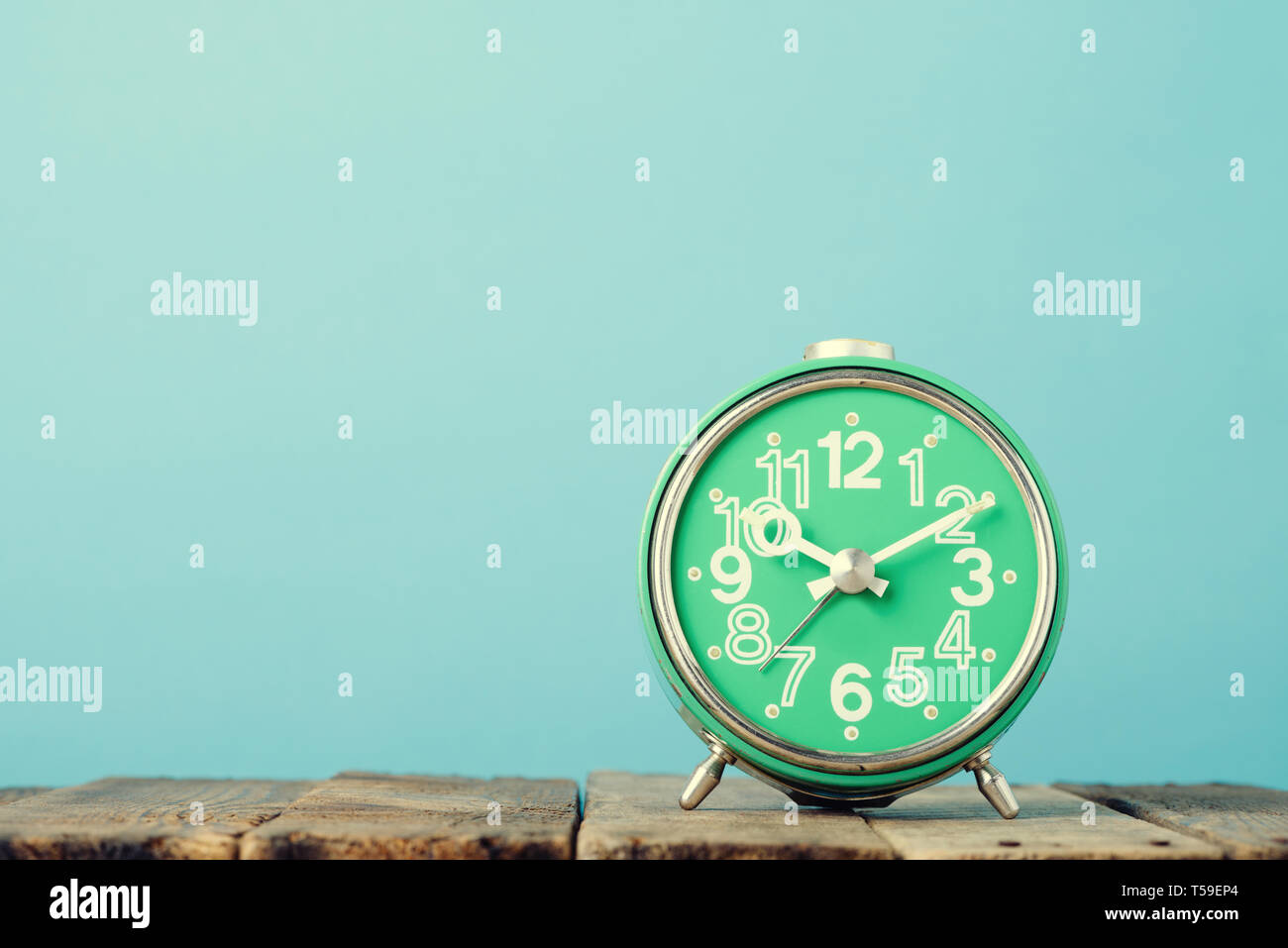 Old vintage clock on wooden table with blue background, vintage toned ...