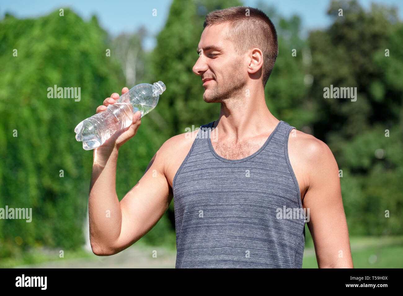 Healthy Lifestyle. Man practicing yoga outdoors standing drinking water ...