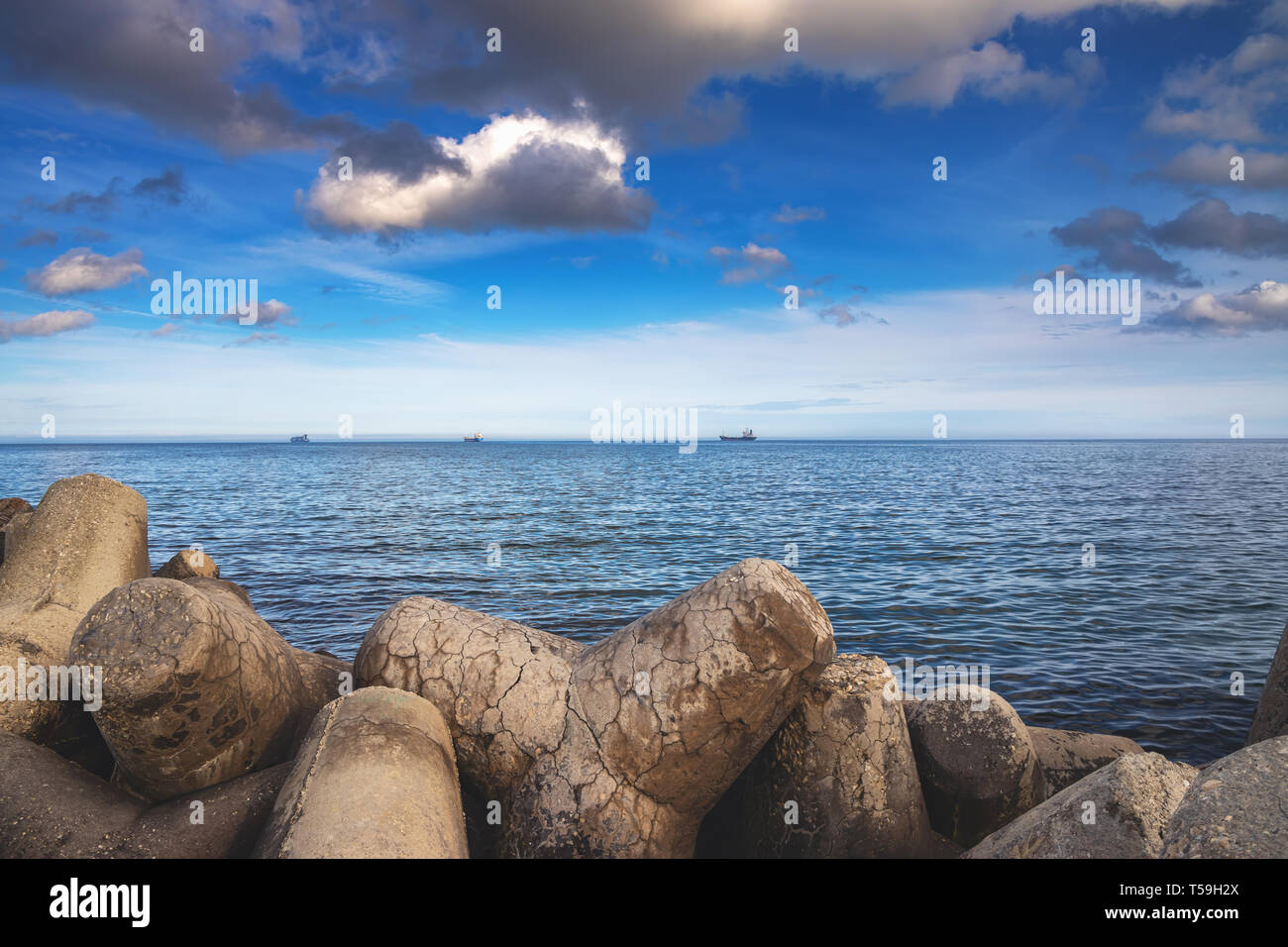 Seascape stones in sea water and sailing cargo ships Stock Photo - Alamy