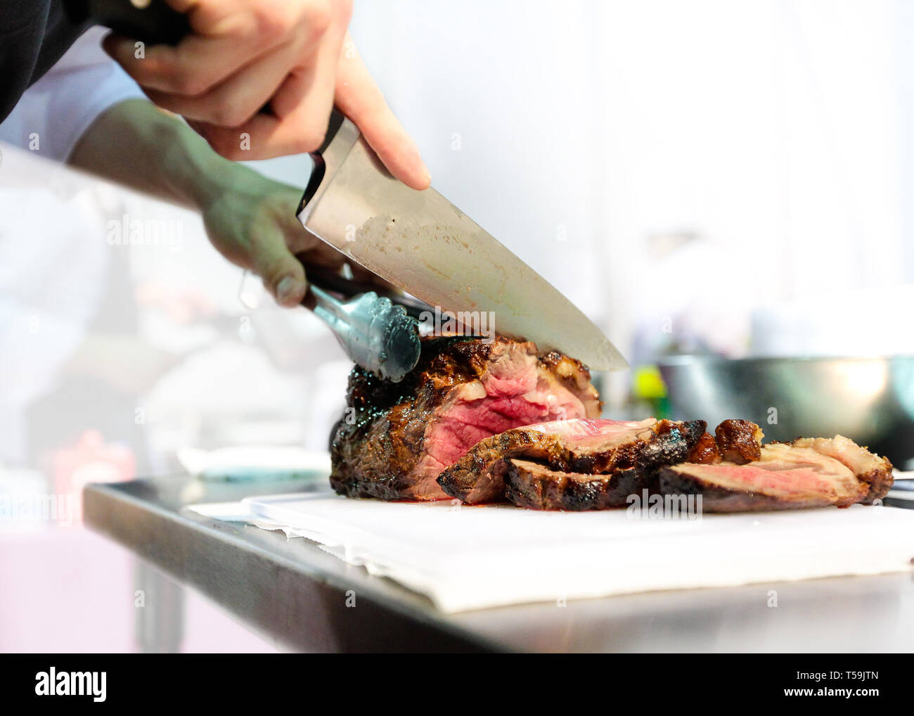 Chef with knife and cutting tasty grilled steak, Chef preparing food ...