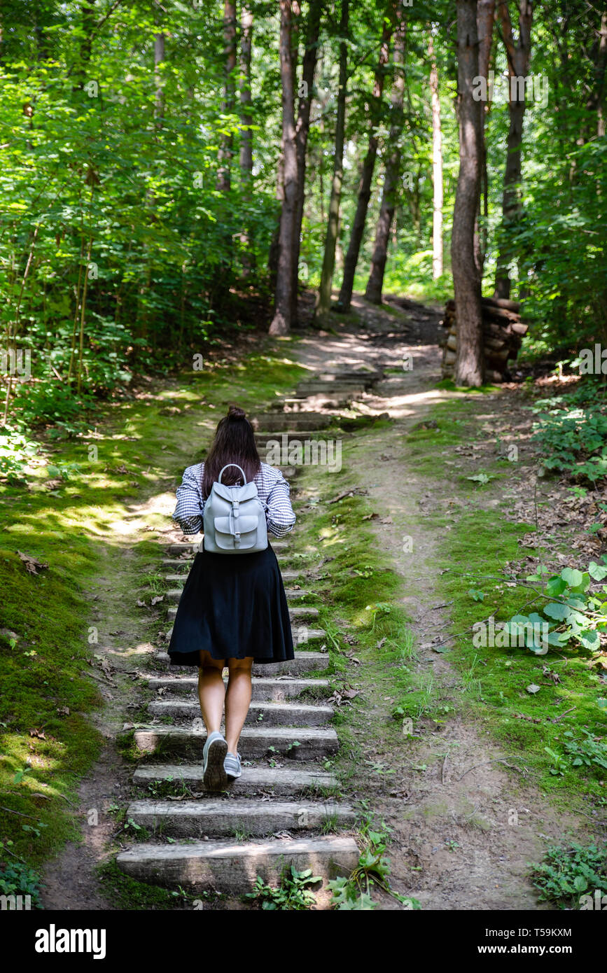 woman walking up by old stairs in forest. view from behind Stock Photo ...