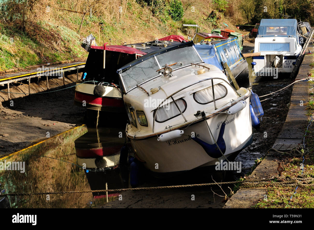 Boats grounded in an empty canal that has been drained for maintenance ...