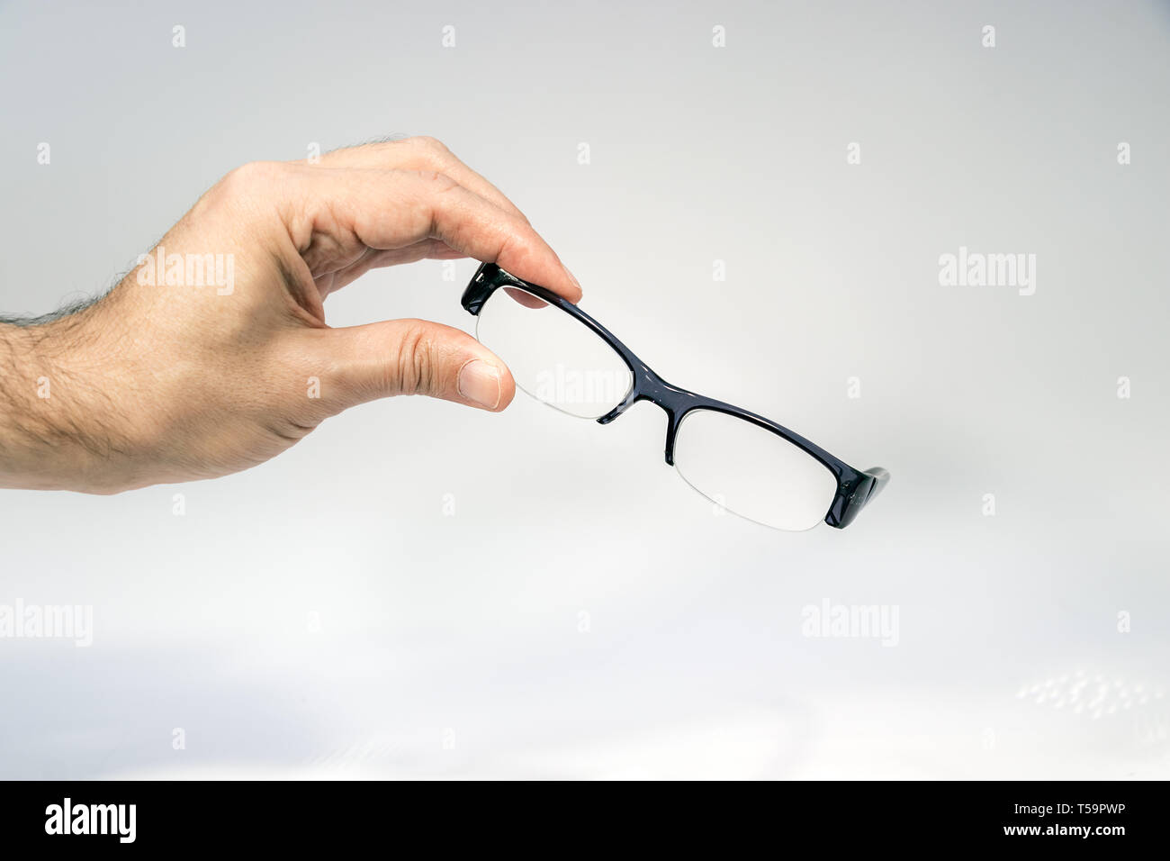 A male hand holding a half frame eyeglasses isolated over white Stock ...