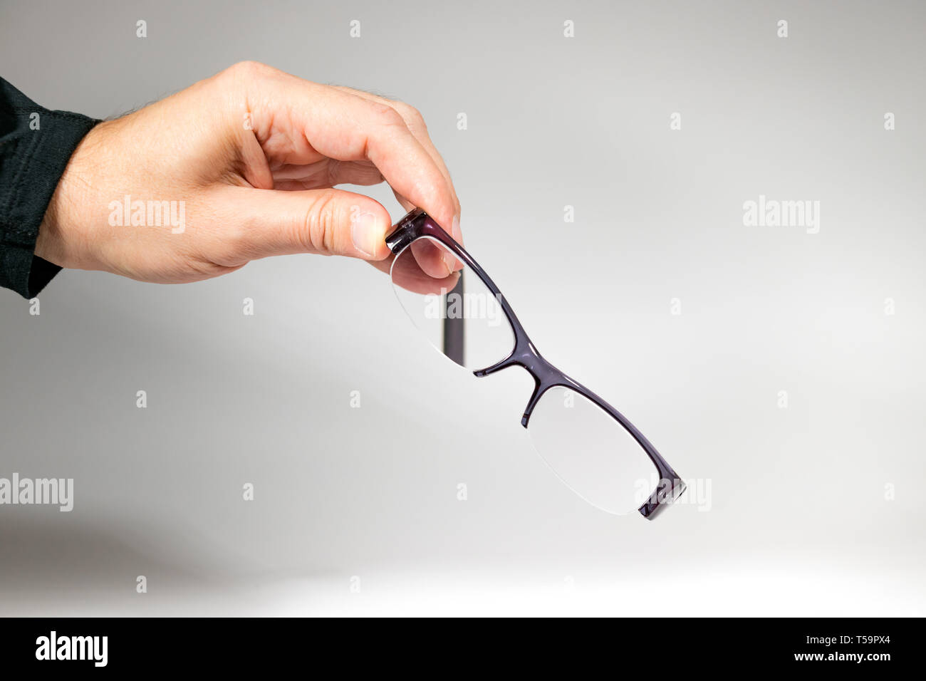 A male hand holding a half frame eyeglasses isolated over white Stock ...