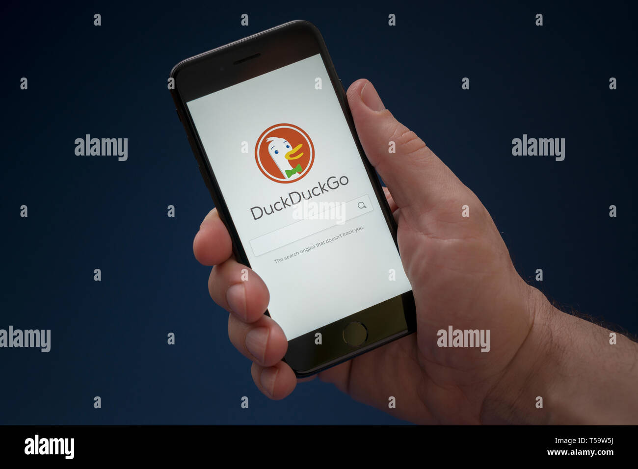 A man looks at his iPhone which displays the DuckDuckGo logo (Editorial ...