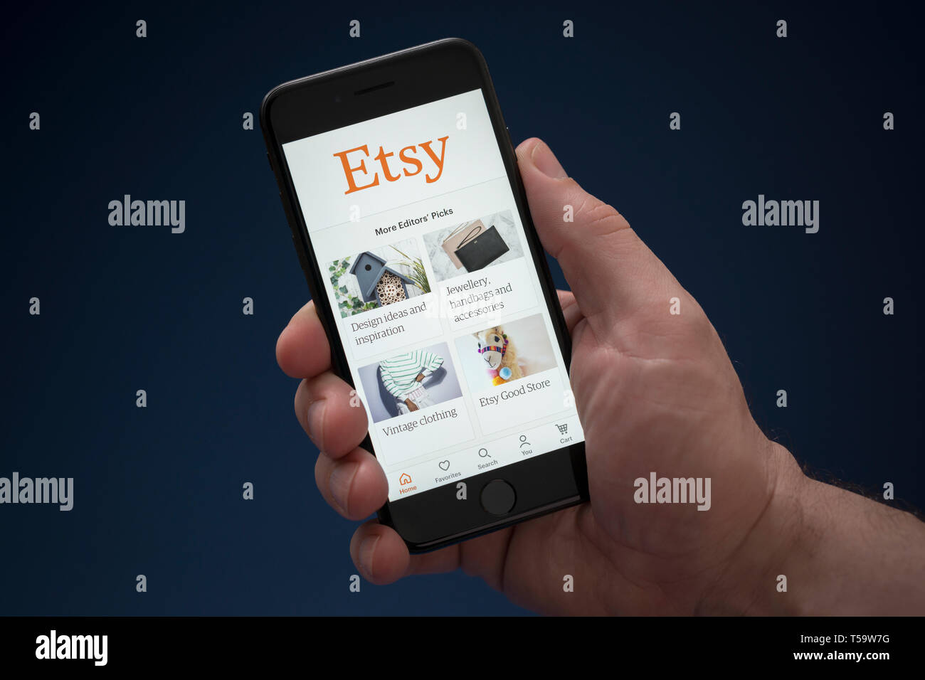 A man looks at his iPhone which displays the Etsy logo (Editorial use ...