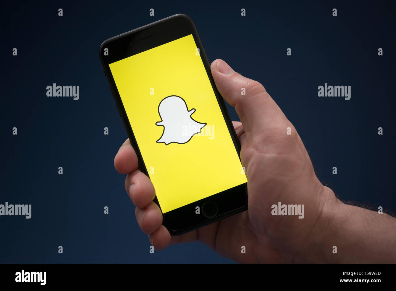 A man looks at his iPhone which displays the Snapchat logo (Editorial ...