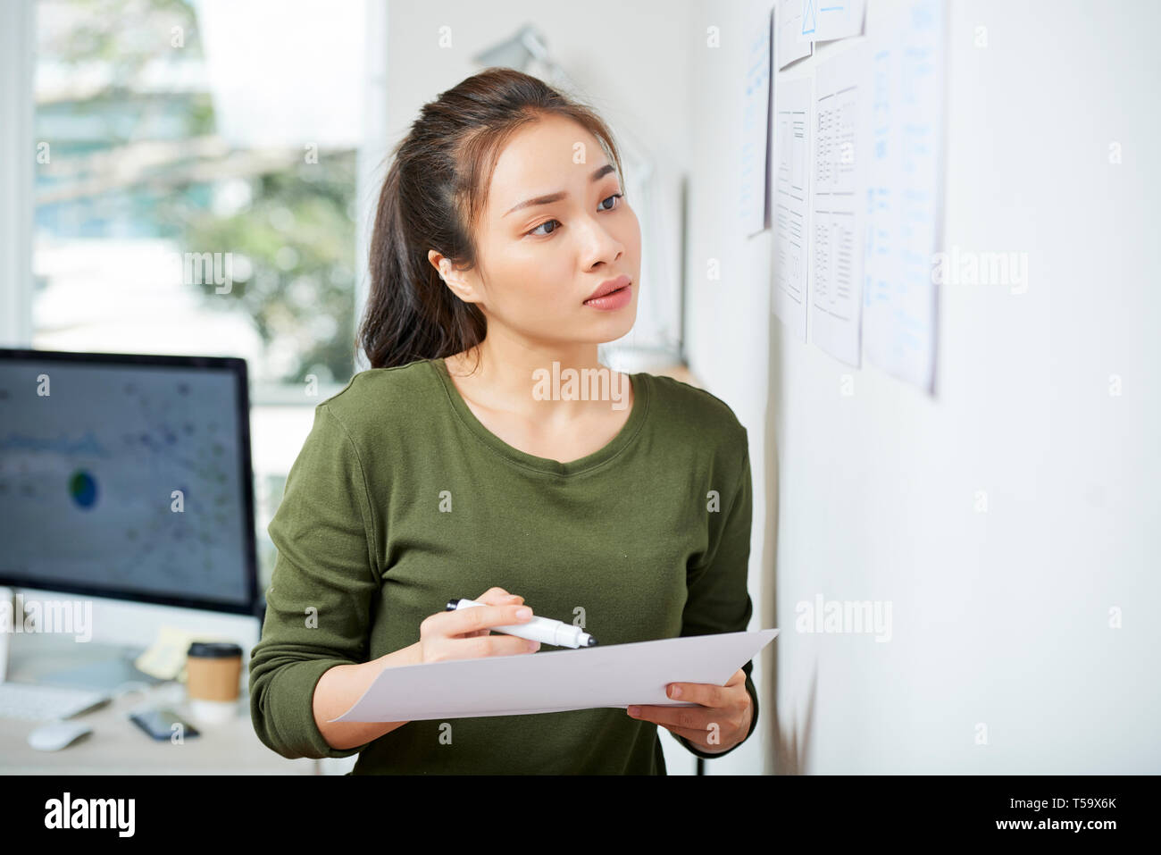 Asian lady comparing data in papers Stock Photo - Alamy