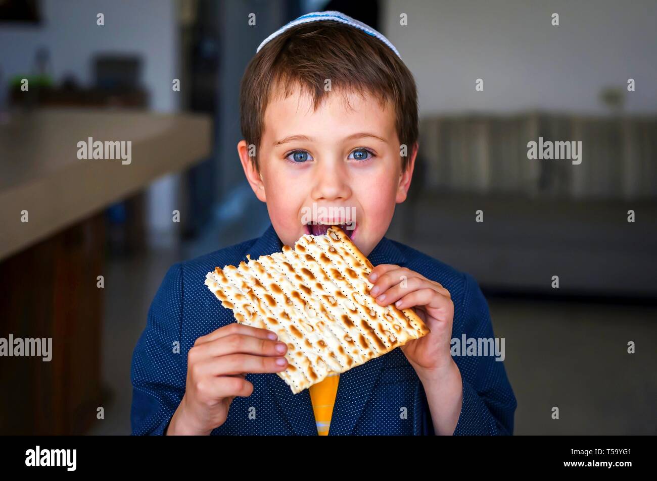 Cute Caucasian child in a yarmulke taking a bite from a traditional ...