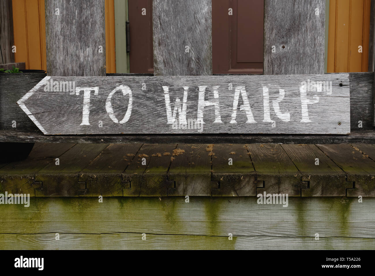 direction sign with words "to wharf" on rustic weathered grey wood ...