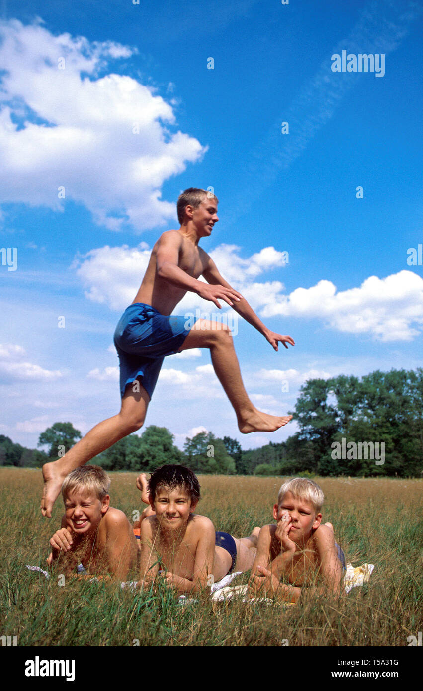boy jumping across three other boys Stock Photo - Alamy