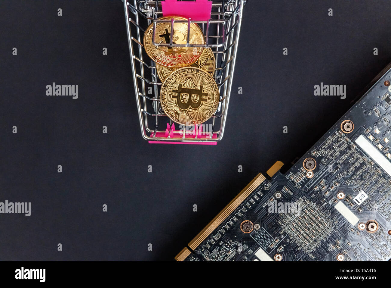 Stack of coins bitcoin in mini shopping cart toy on the video card ...